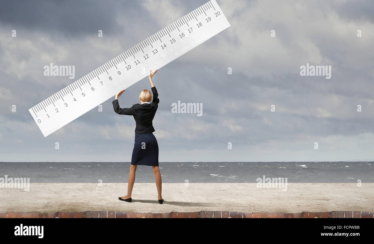 Young businesswoman measuring something with big ruler Stock Photo - Alamy