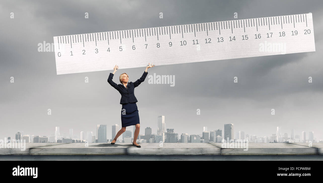Young businesswoman measuring something with big ruler Stock Photo - Alamy