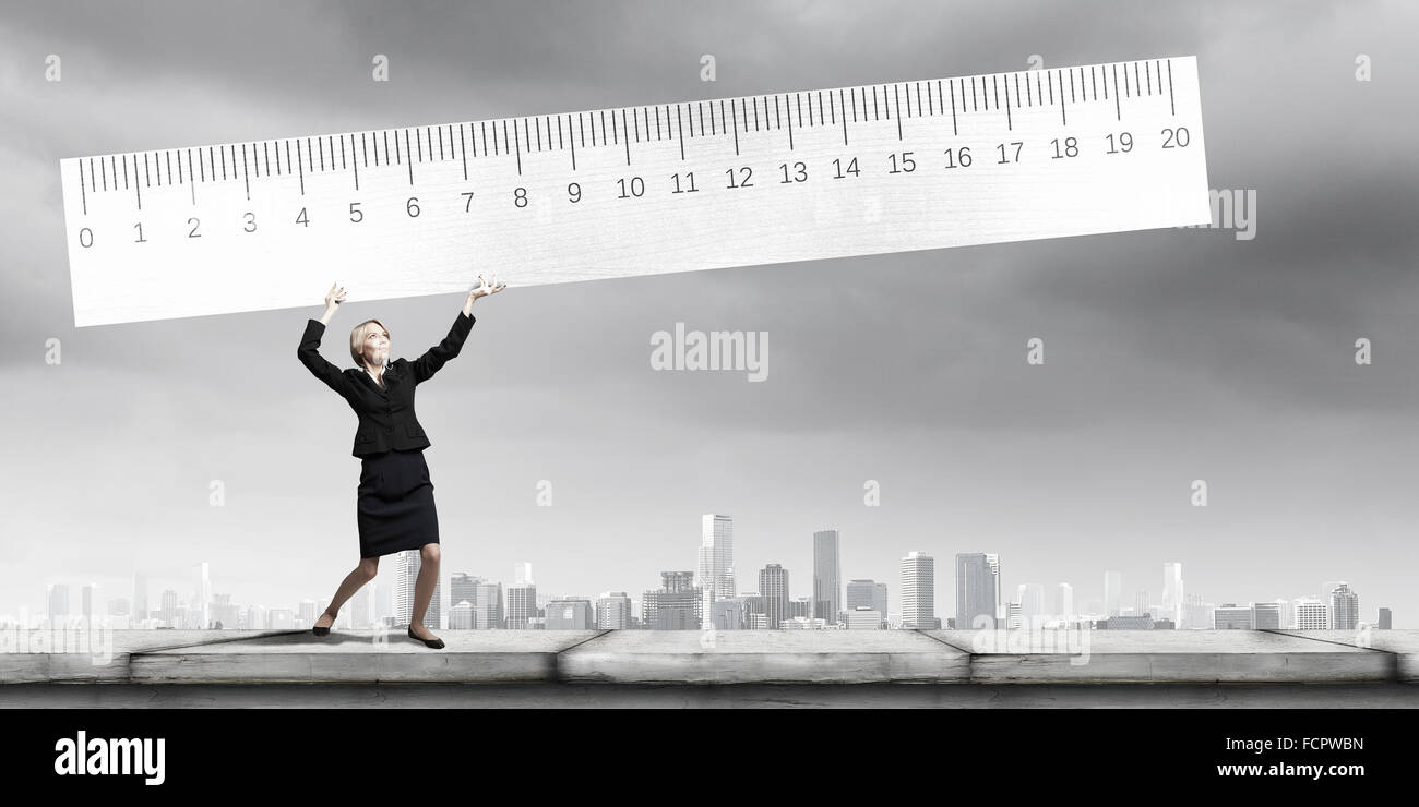 Young businesswoman measuring something with big ruler Stock Photo - Alamy