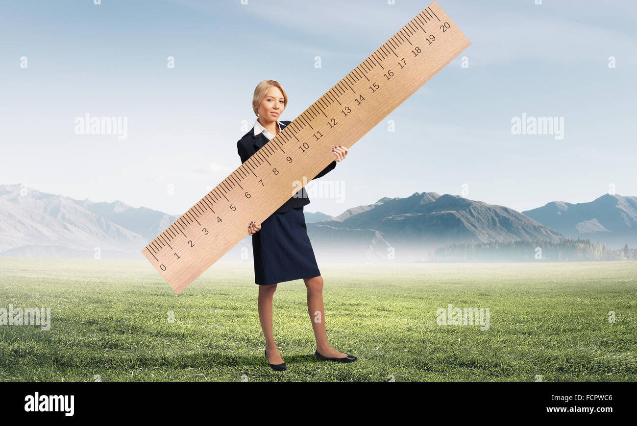 Young businesswoman measuring something with big ruler Stock Photo - Alamy