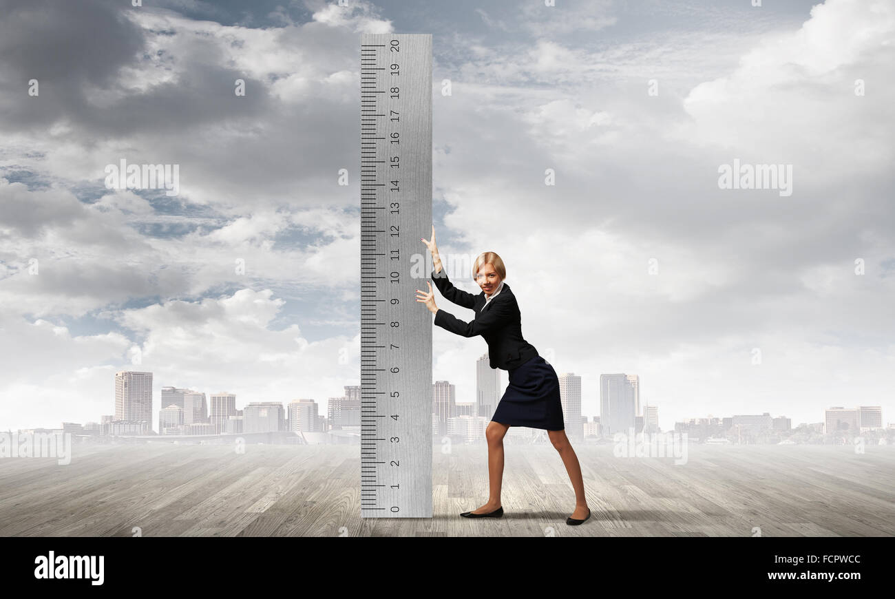 Young businesswoman measuring something with big ruler Stock Photo - Alamy
