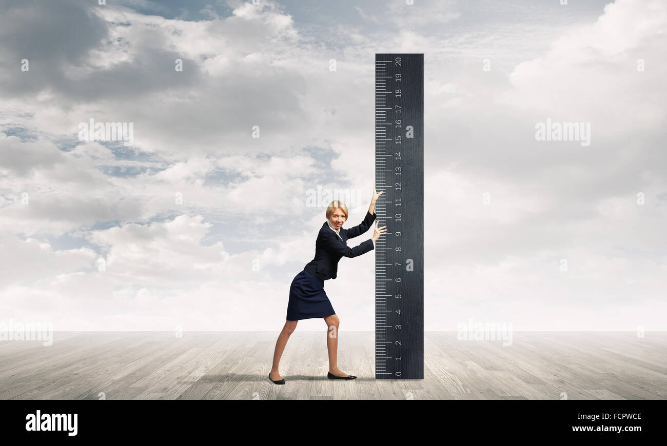 Young businesswoman measuring something with big ruler Stock Photo - Alamy