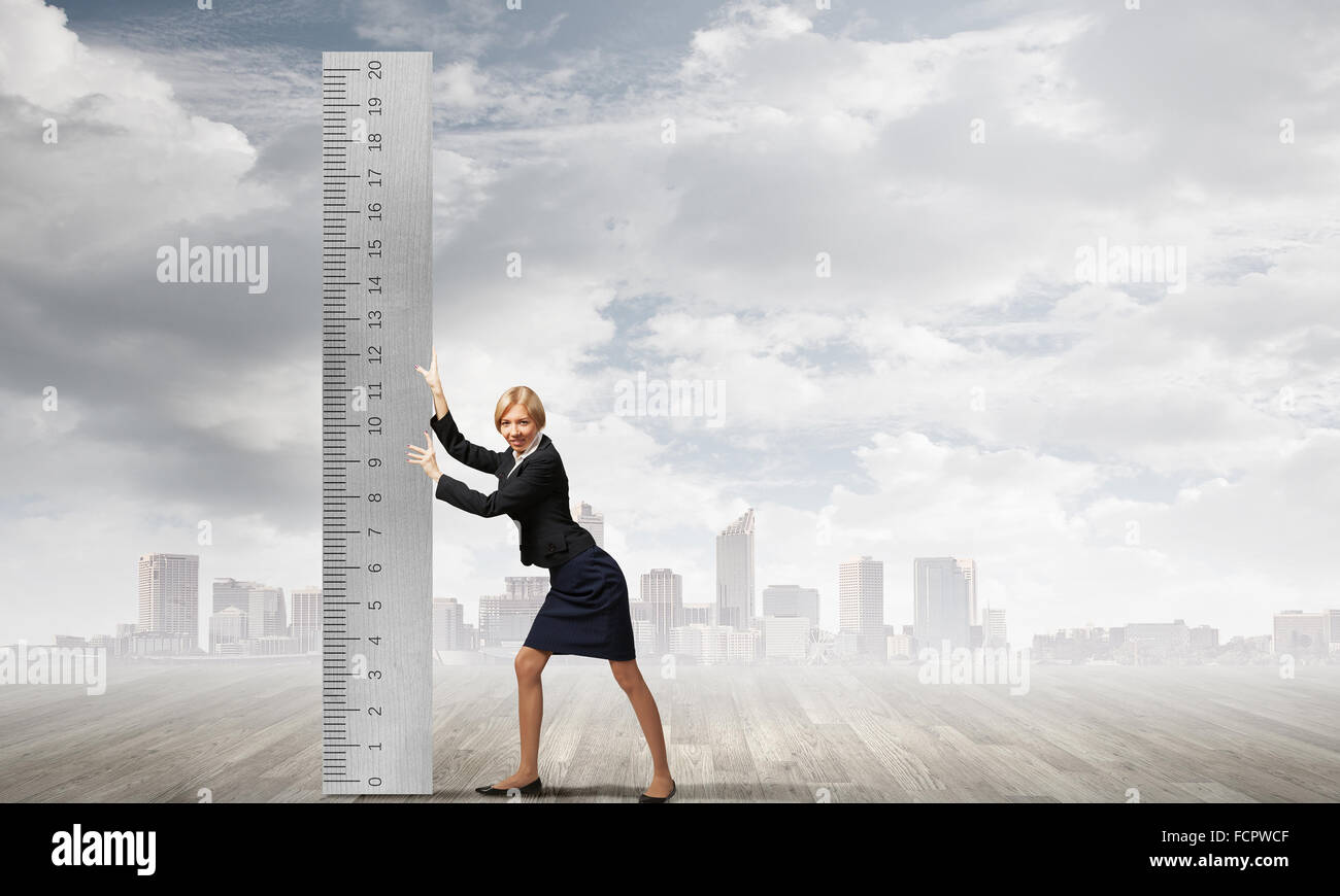 Young businesswoman measuring something with big ruler Stock Photo - Alamy