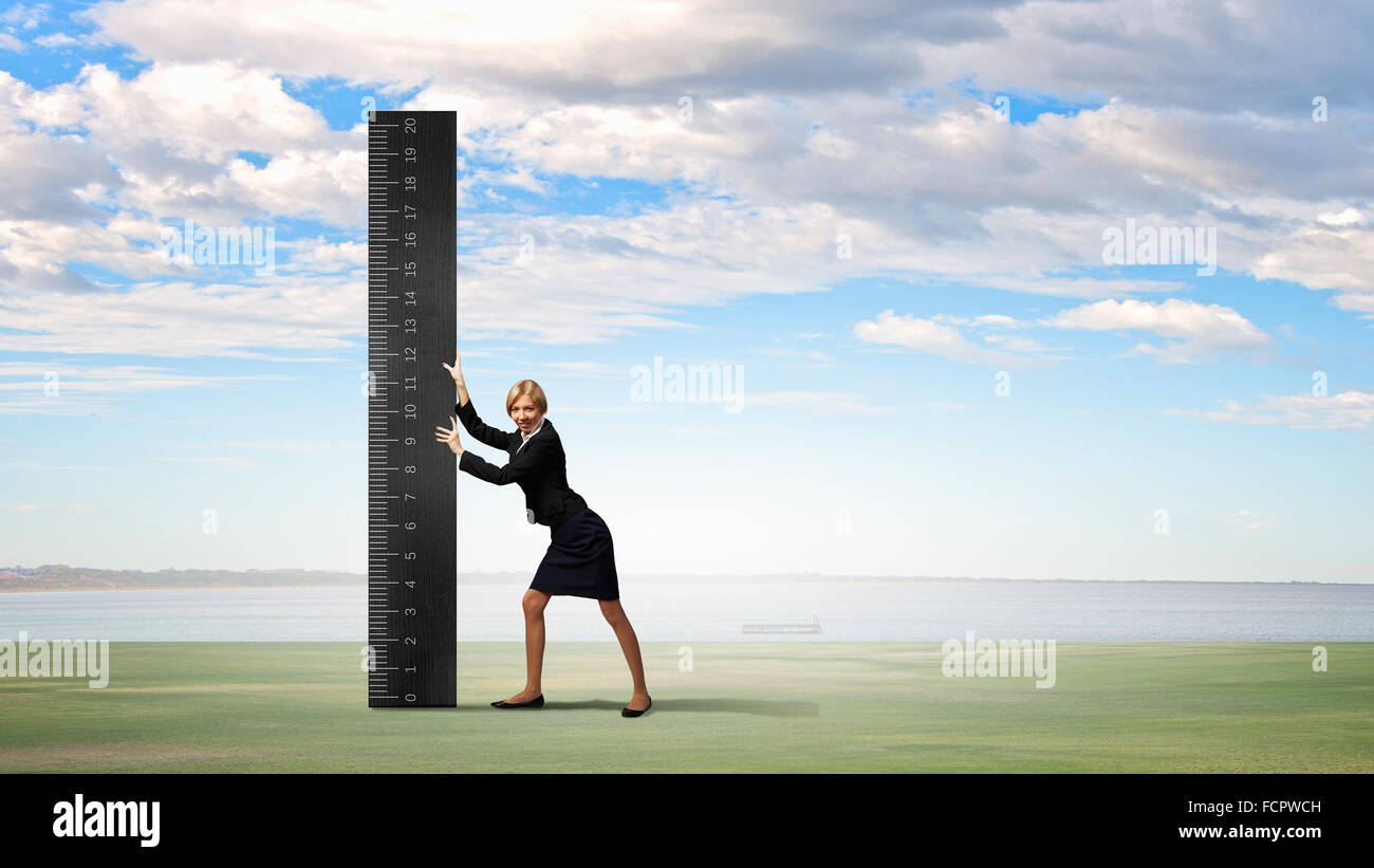 Young businesswoman measuring something with big ruler Stock Photo - Alamy