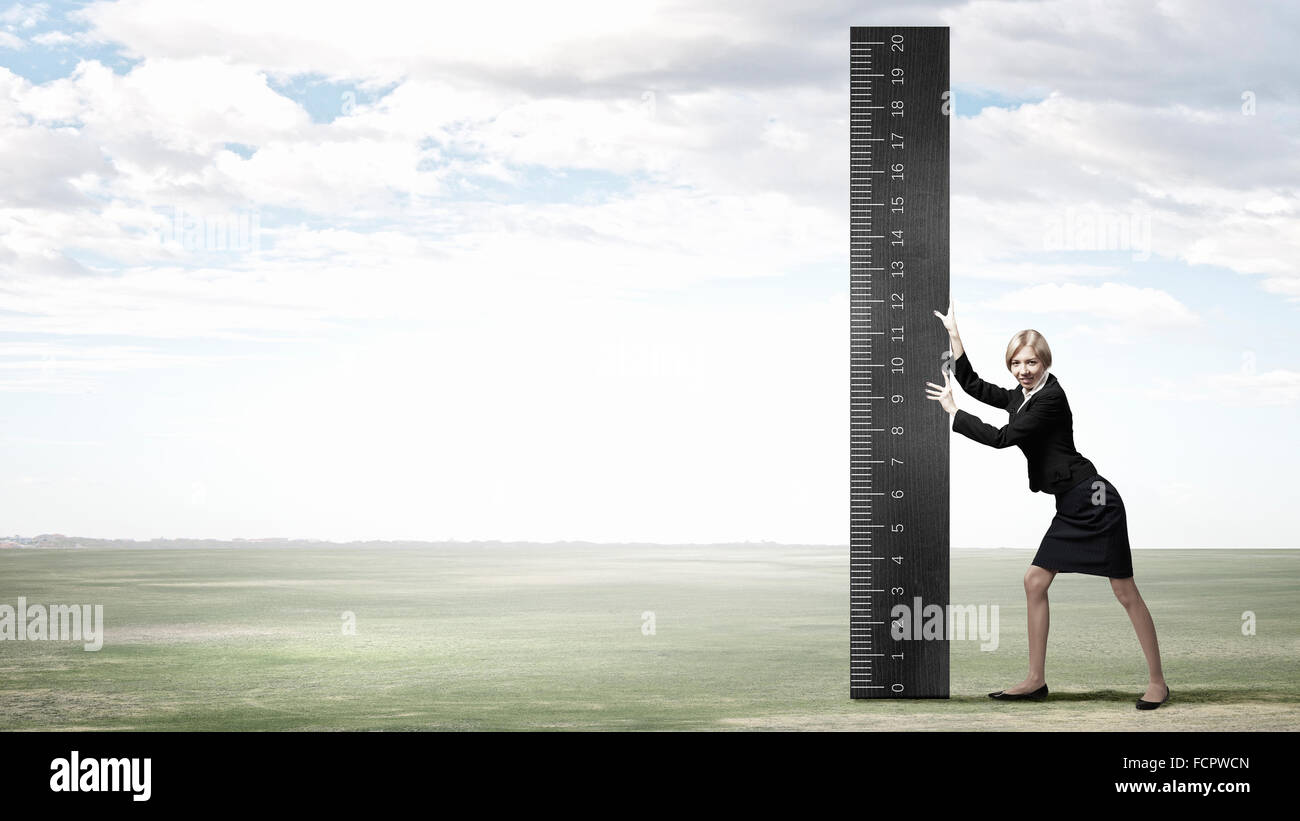 Young businesswoman measuring something with big ruler Stock Photo - Alamy