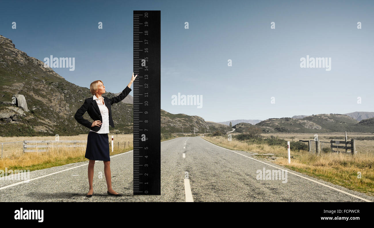 Young businesswoman measuring something with big ruler Stock Photo - Alamy