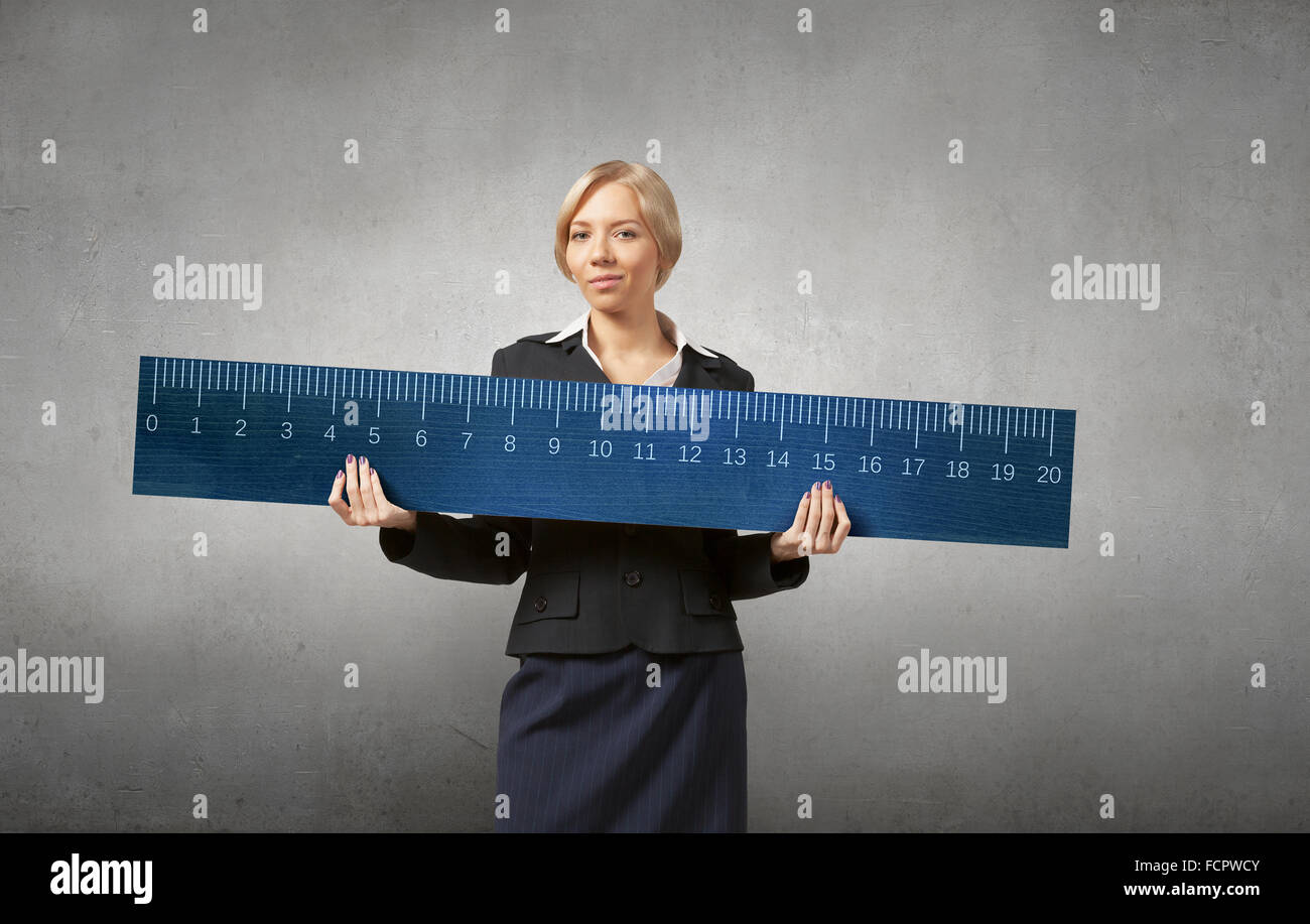 Young businesswoman measuring something with big ruler Stock Photo - Alamy