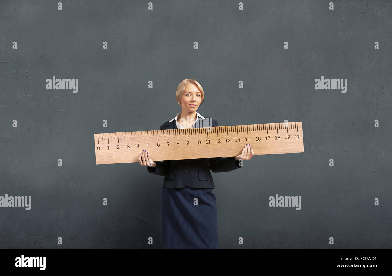 Young businesswoman measuring something with big ruler Stock Photo - Alamy