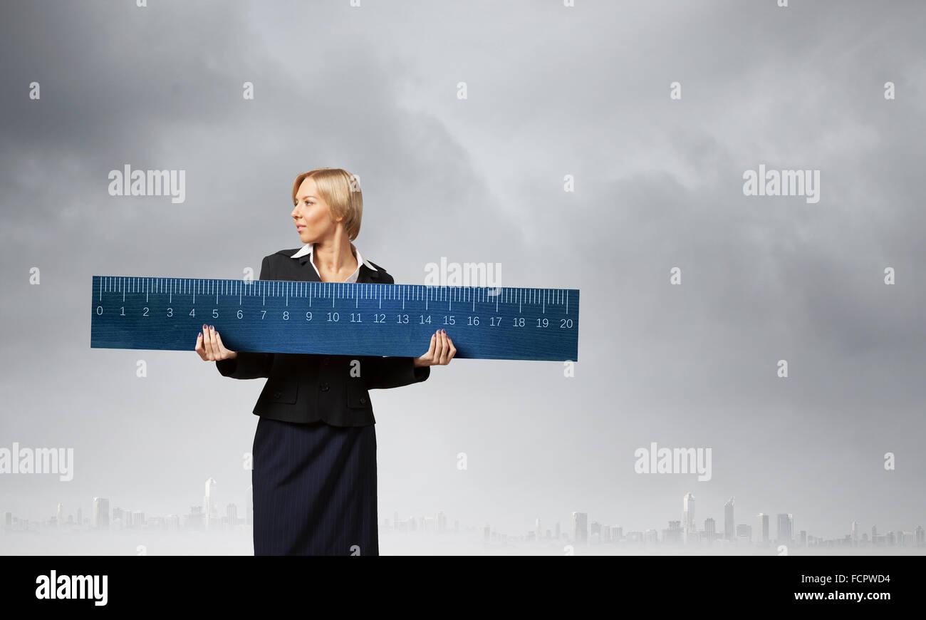 Young businesswoman measuring something with big ruler Stock Photo - Alamy