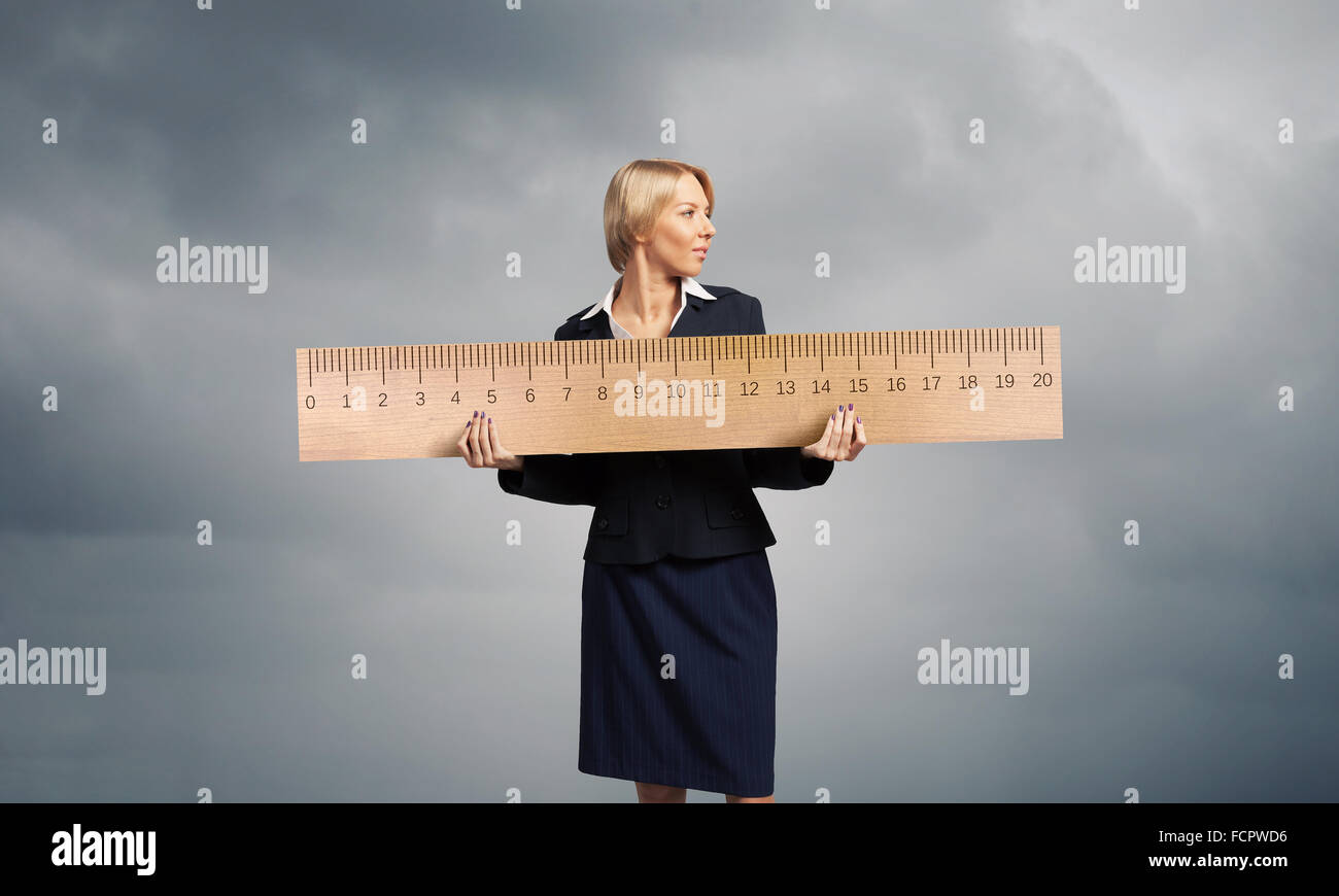 Young businesswoman measuring something with big ruler Stock Photo - Alamy