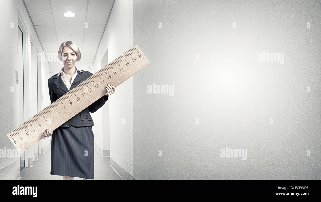 Young businesswoman measuring something with big ruler Stock Photo - Alamy