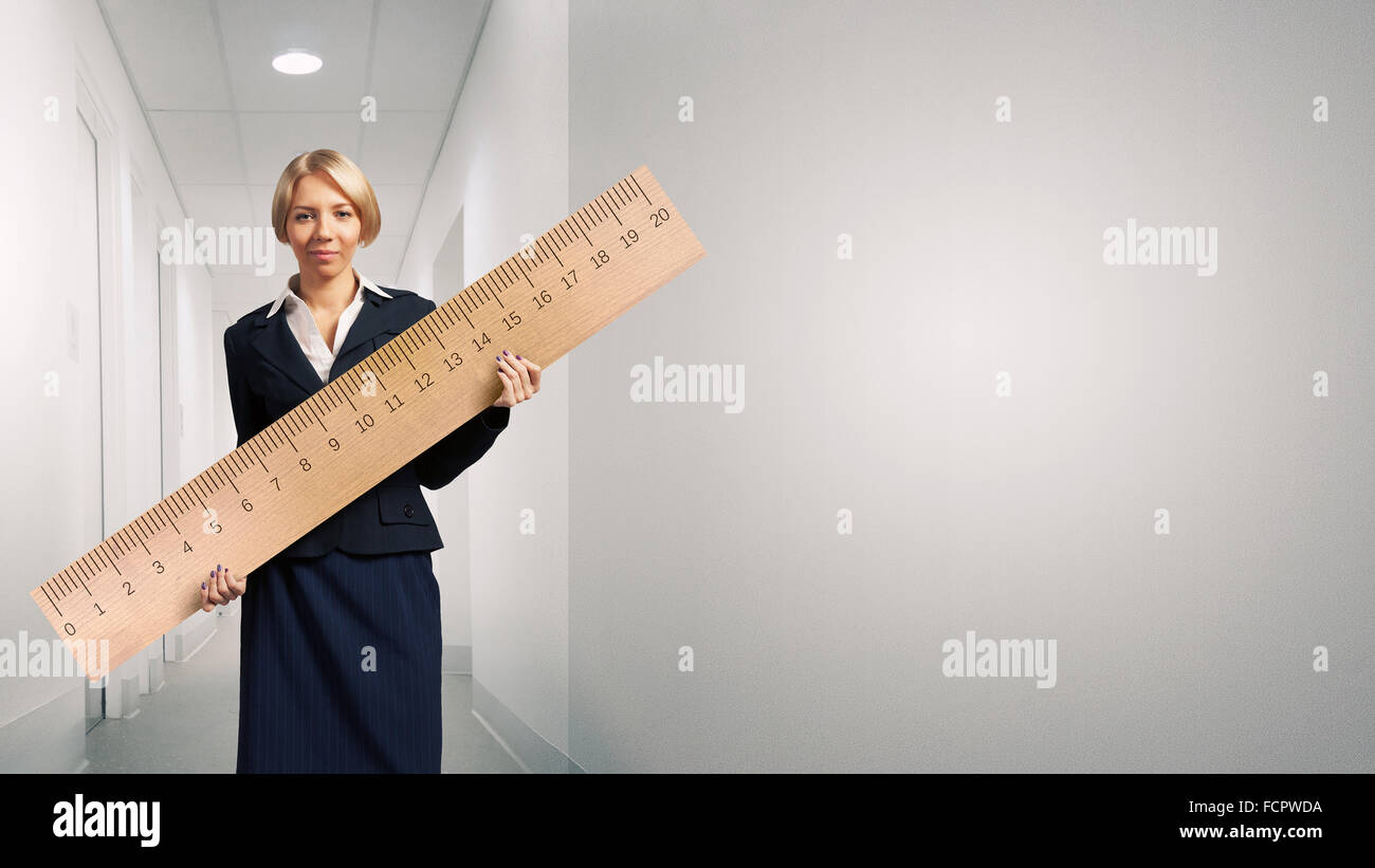 Young businesswoman measuring something with big ruler Stock Photo - Alamy