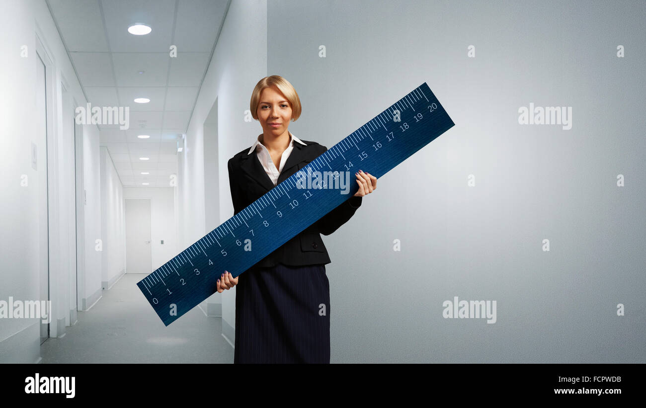 Young businesswoman measuring something with big ruler Stock Photo - Alamy