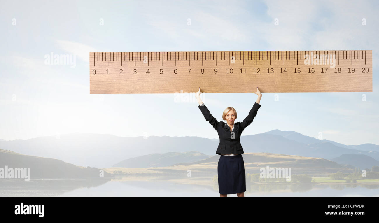 Young businesswoman measuring something with big ruler Stock Photo - Alamy