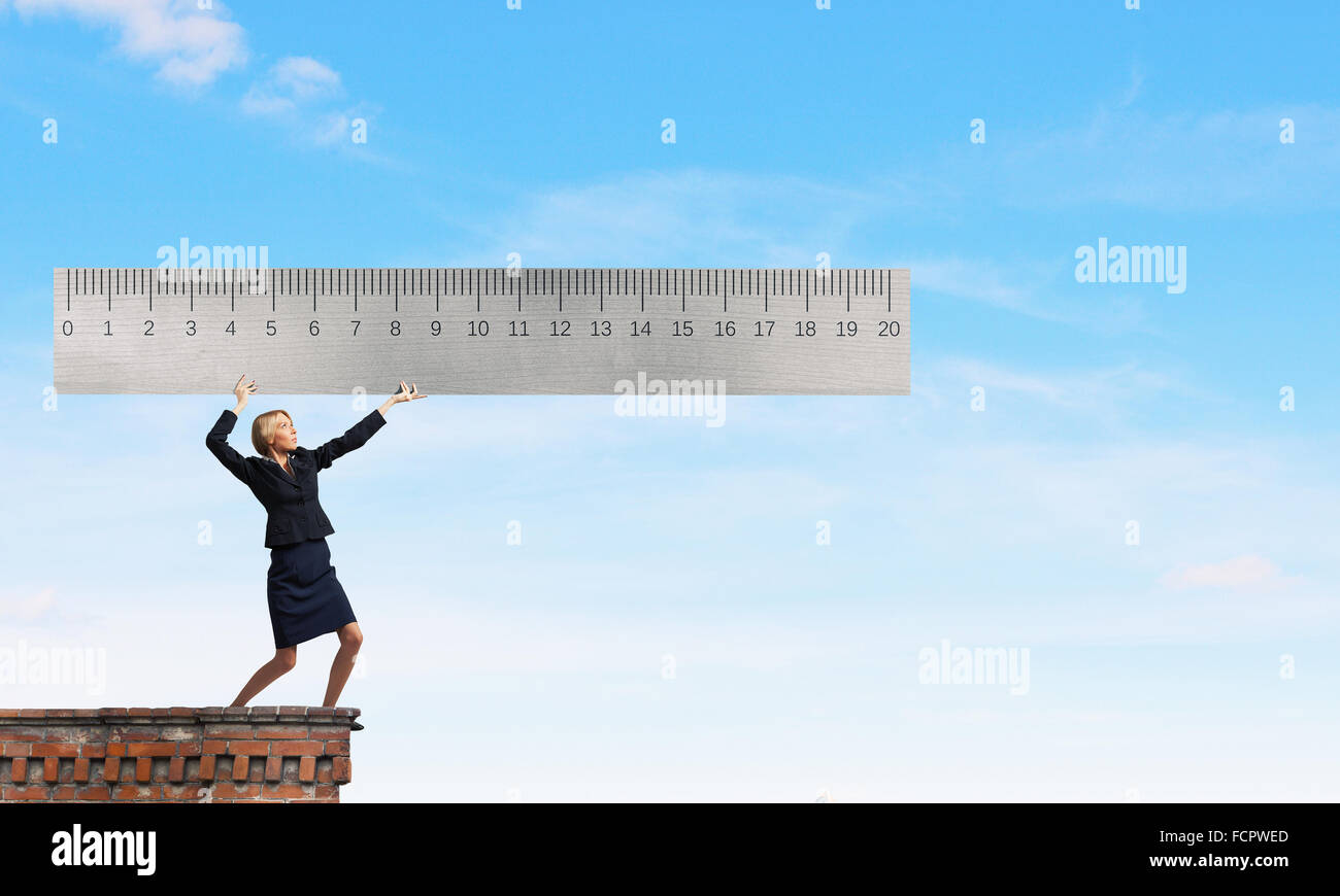 Young businesswoman measuring something with big ruler Stock Photo - Alamy