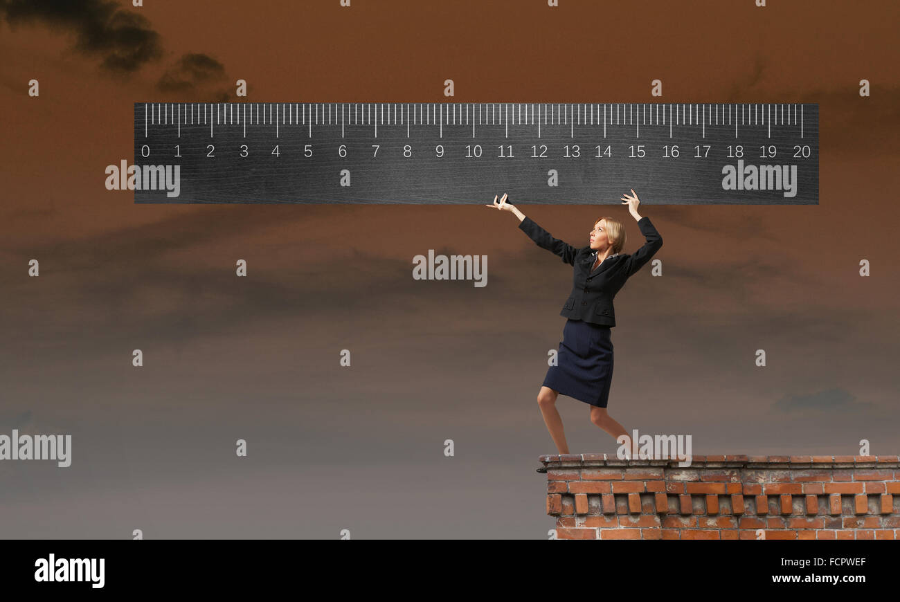 Young businesswoman measuring something with big ruler Stock Photo - Alamy