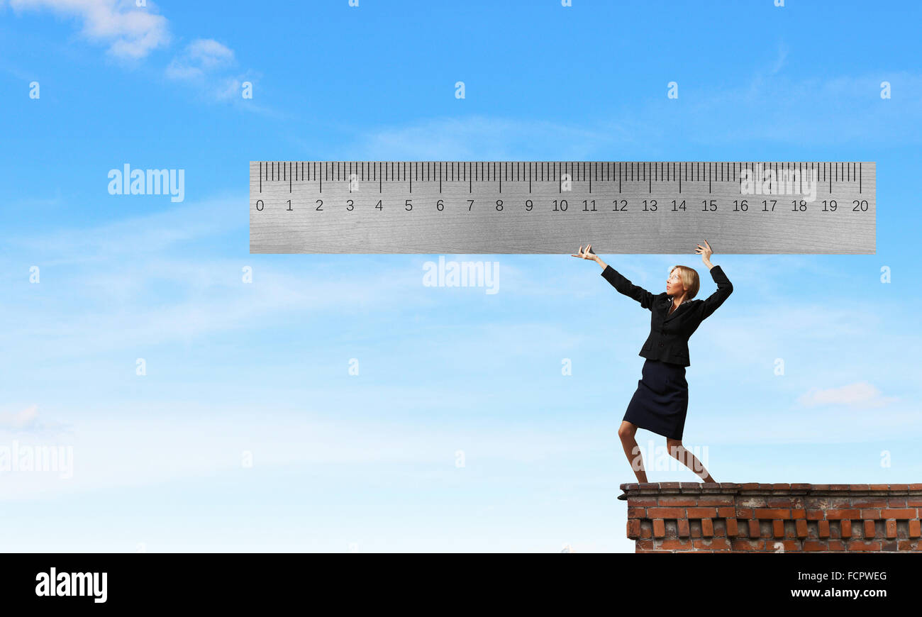 Young businesswoman measuring something with big ruler Stock Photo - Alamy