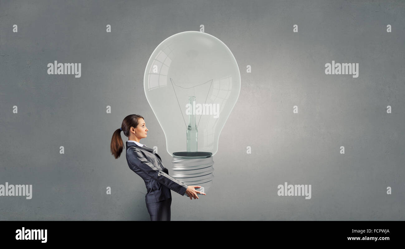 Young businesswoman carrying big light bulb in hands Stock Photo - Alamy