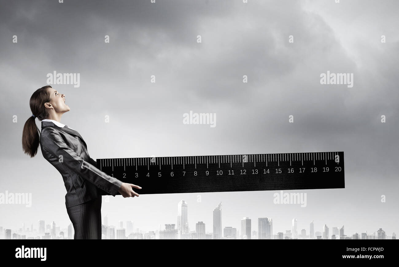 Young businesswoman measuring something with big ruler Stock Photo - Alamy