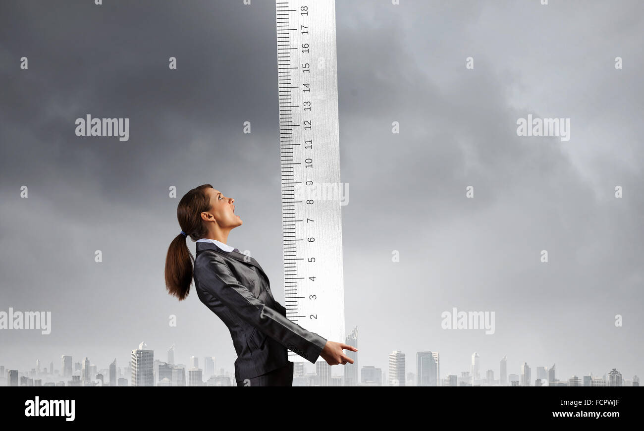 Young businesswoman measuring something with big ruler Stock Photo - Alamy