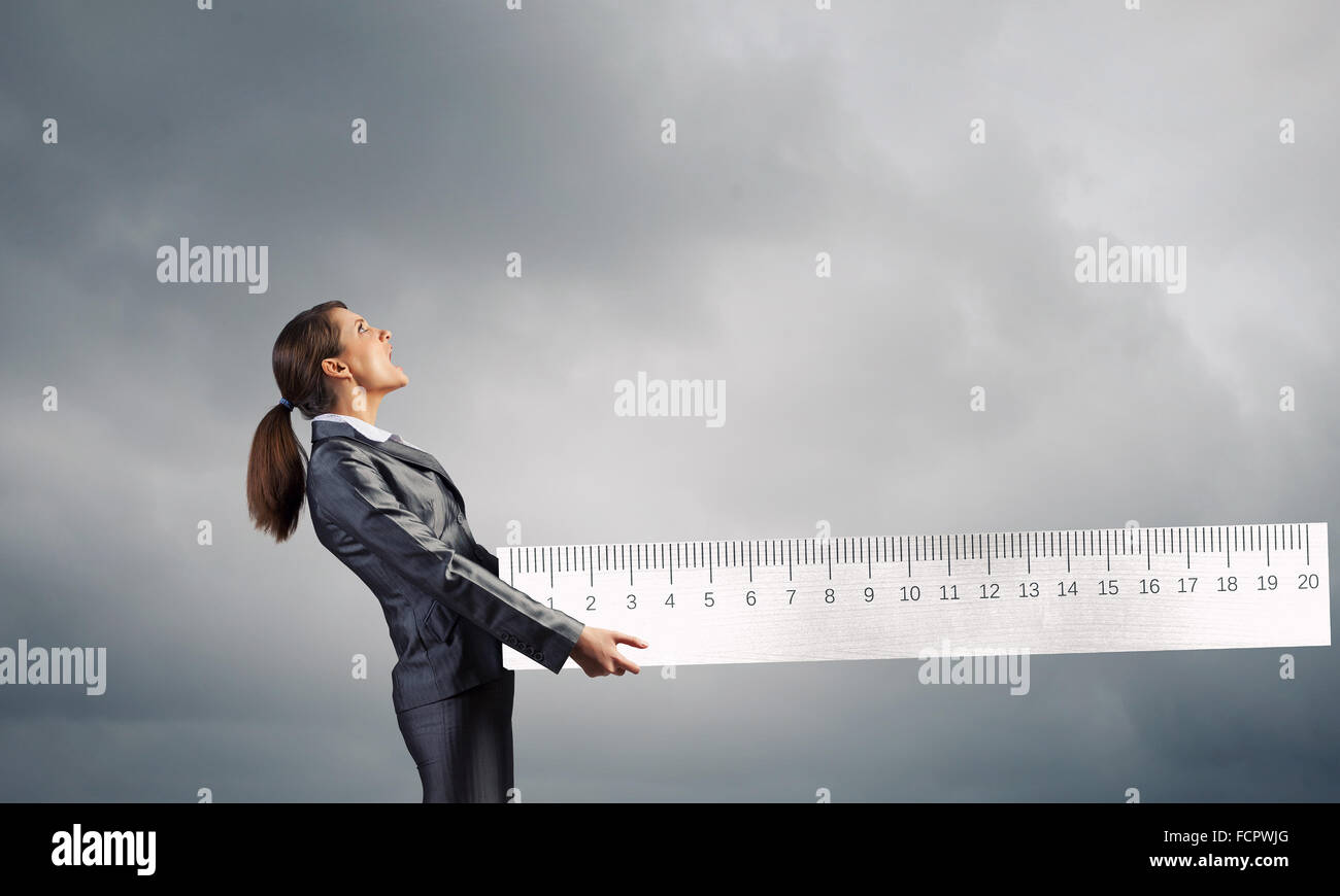 Young businesswoman measuring something with big ruler Stock Photo - Alamy
