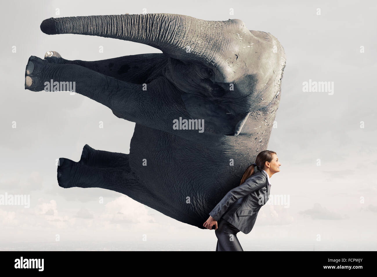 Young pretty elegant businesswoman lifting heavy elephant Stock Photo ...