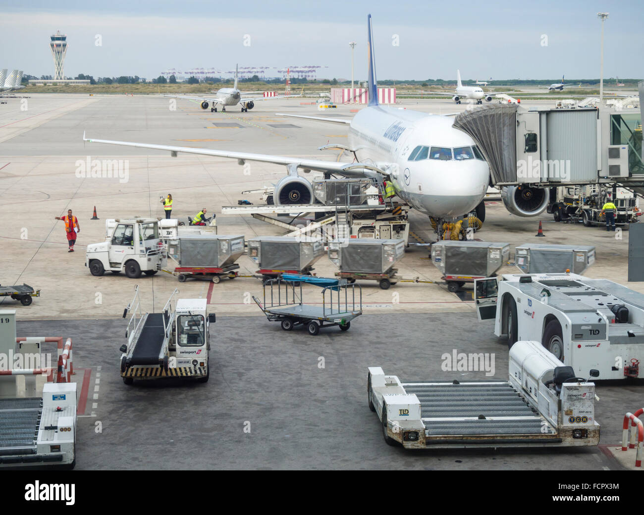 Aircraft being loaded at Barcelona airport. Busy workers, baggage carts ...