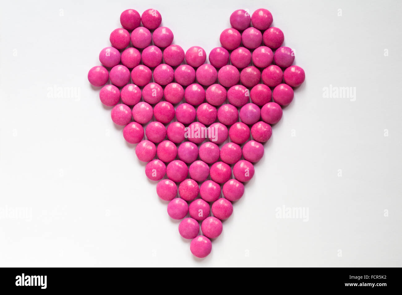 Pink smarties arranged in the shape of a heart hi-res stock photography ...