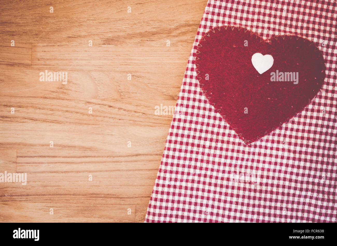 checkered cotton fabric and heart felt decoration on a wood background ...