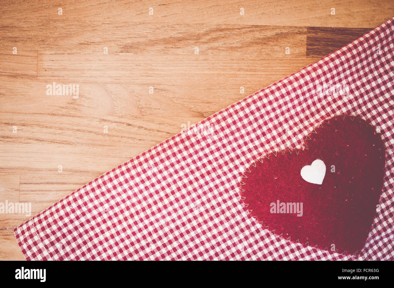 checkered cotton fabric and heart felt decoration on a wood background ...