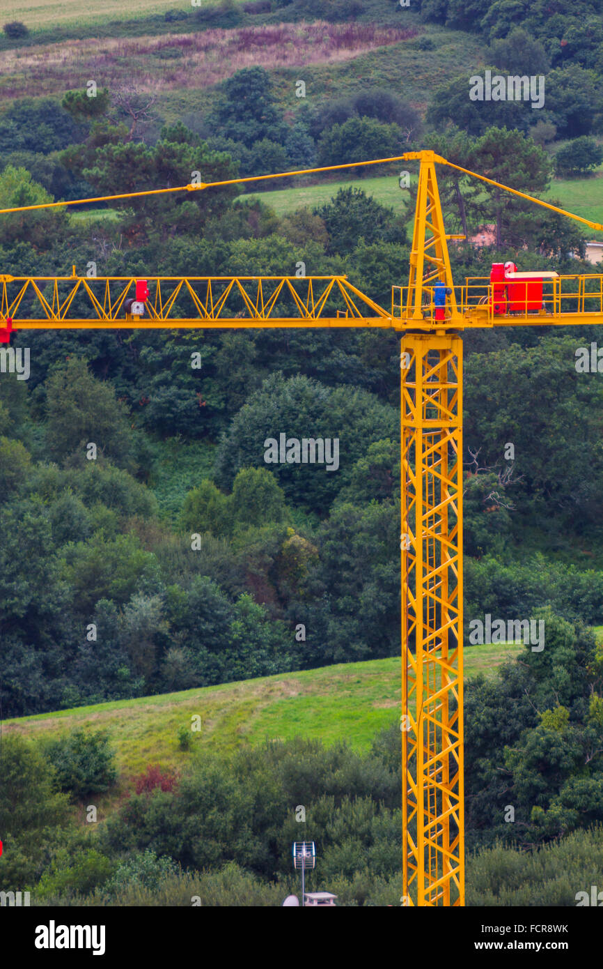 yellow construction crane on background of green forest Stock Photo - Alamy