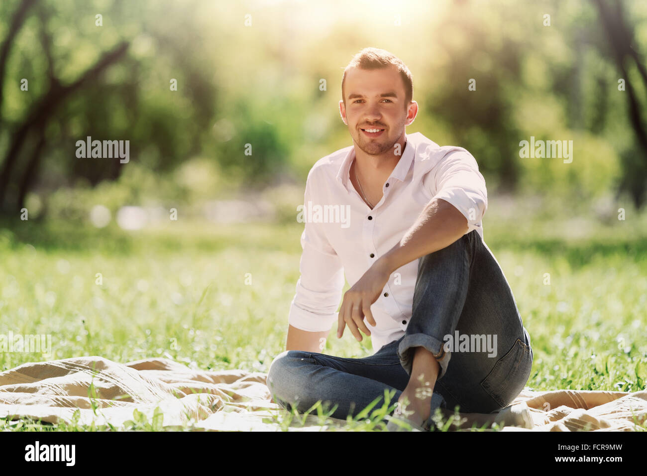 Handsome man sitting on the green grass in park Stock Photo - Alamy