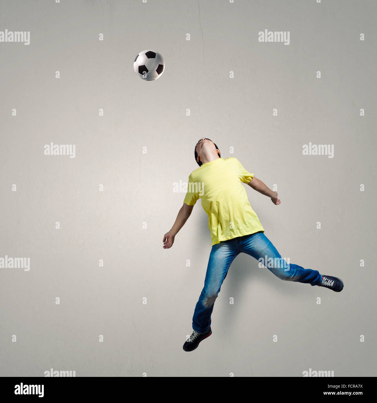 Man in casual kick football ball over head Stock Photo - Alamy