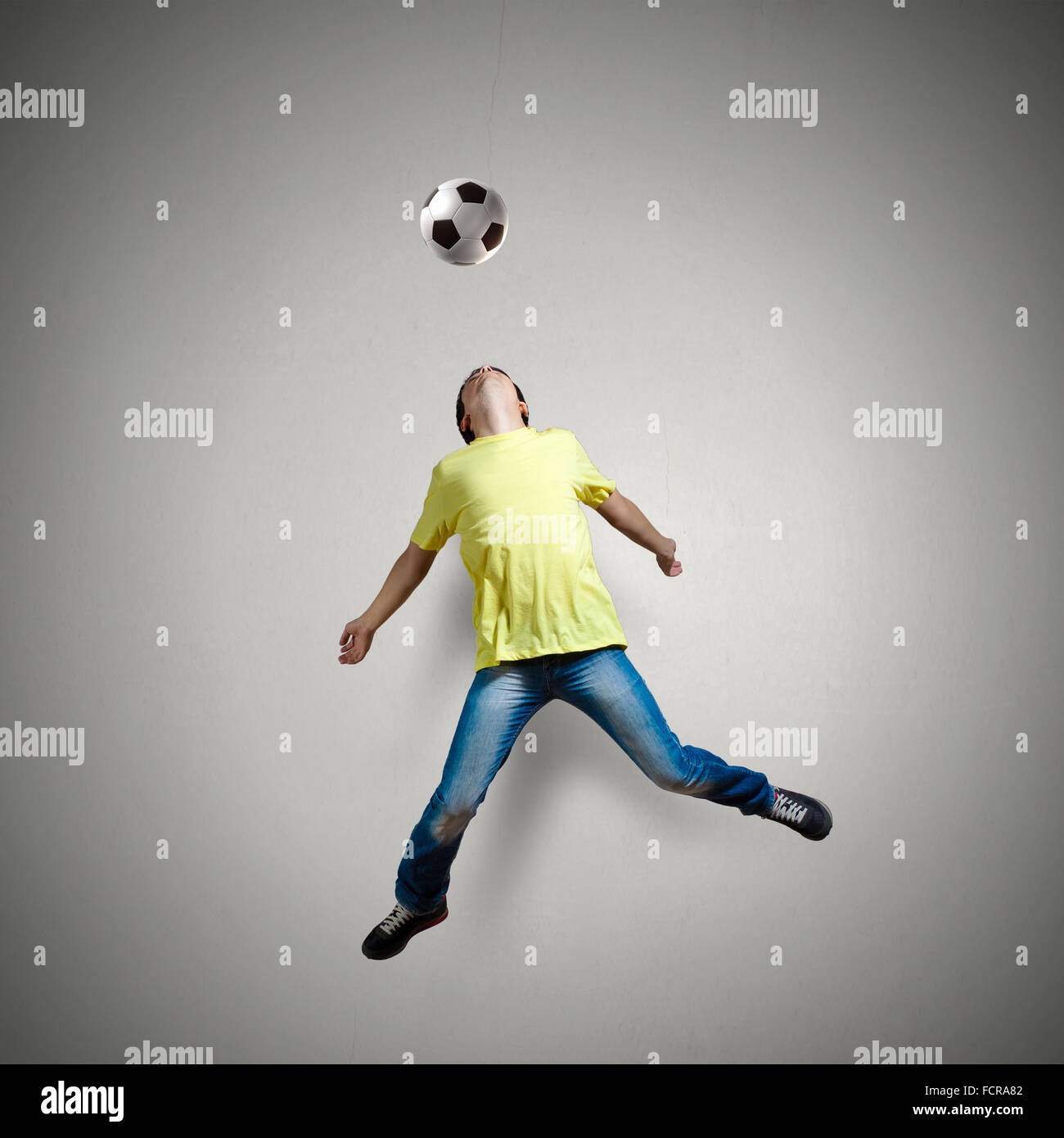 Man in casual kick football ball over head Stock Photo - Alamy