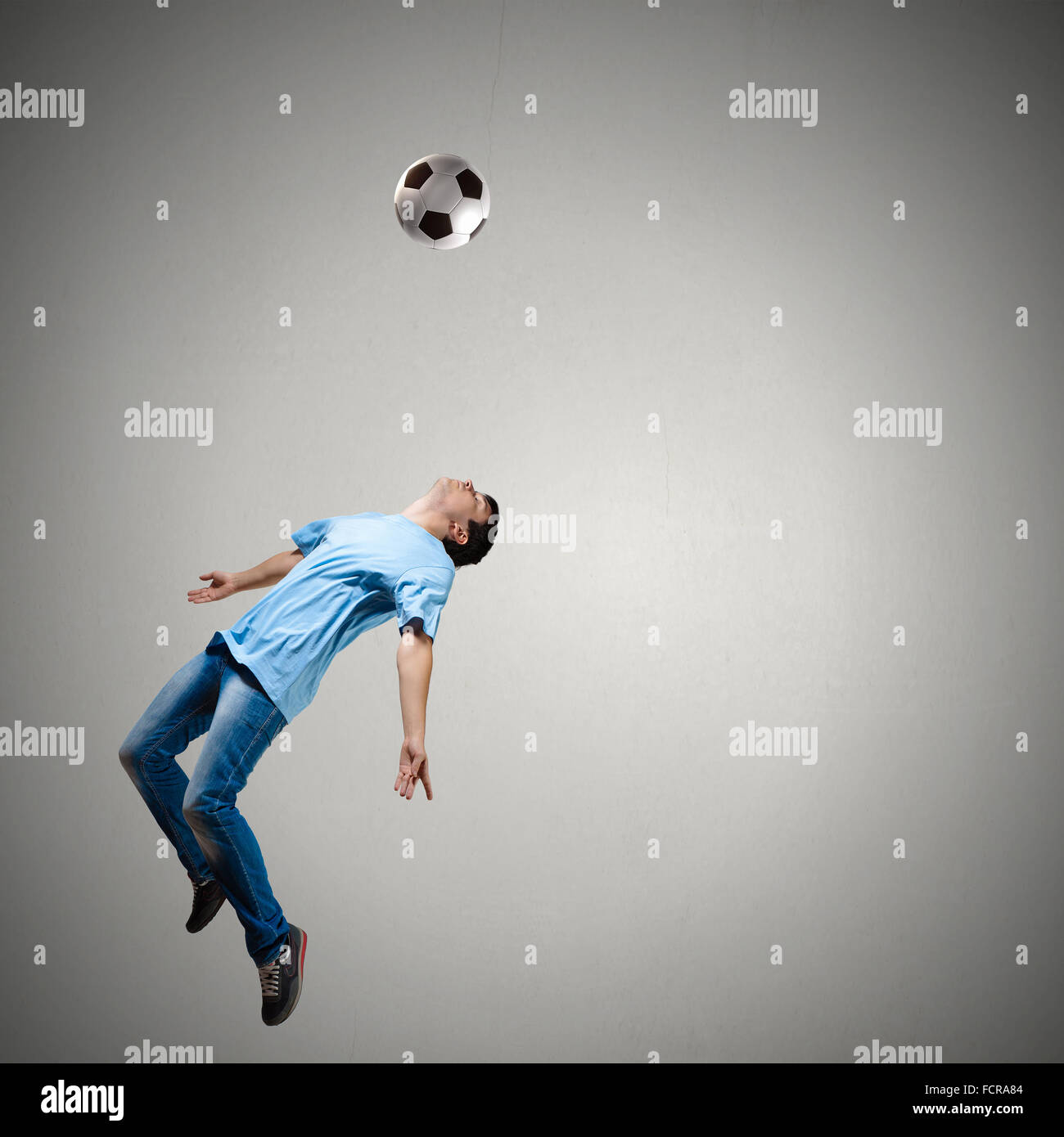 Man in casual kick football ball over head Stock Photo - Alamy