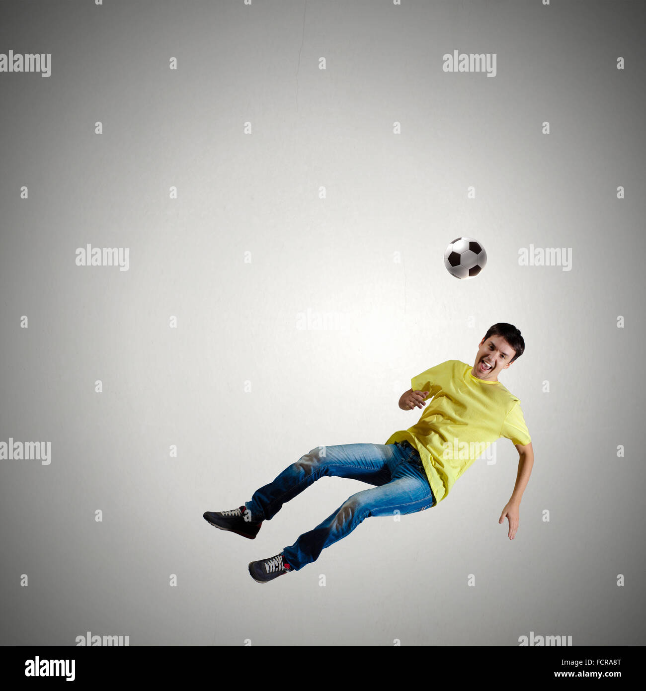 Man in casual kick football ball over head Stock Photo - Alamy