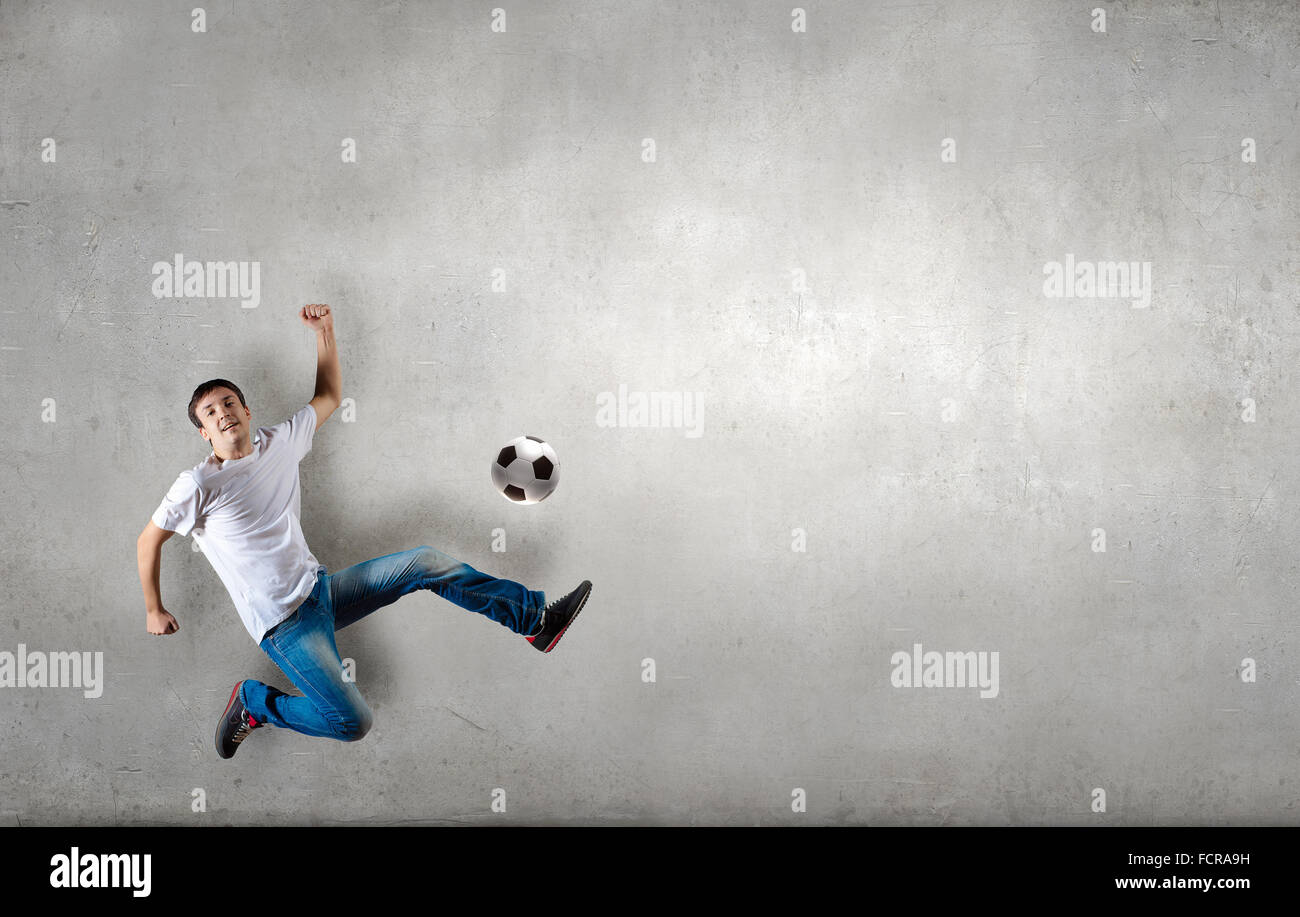 Man in casual kick football ball over head Stock Photo - Alamy