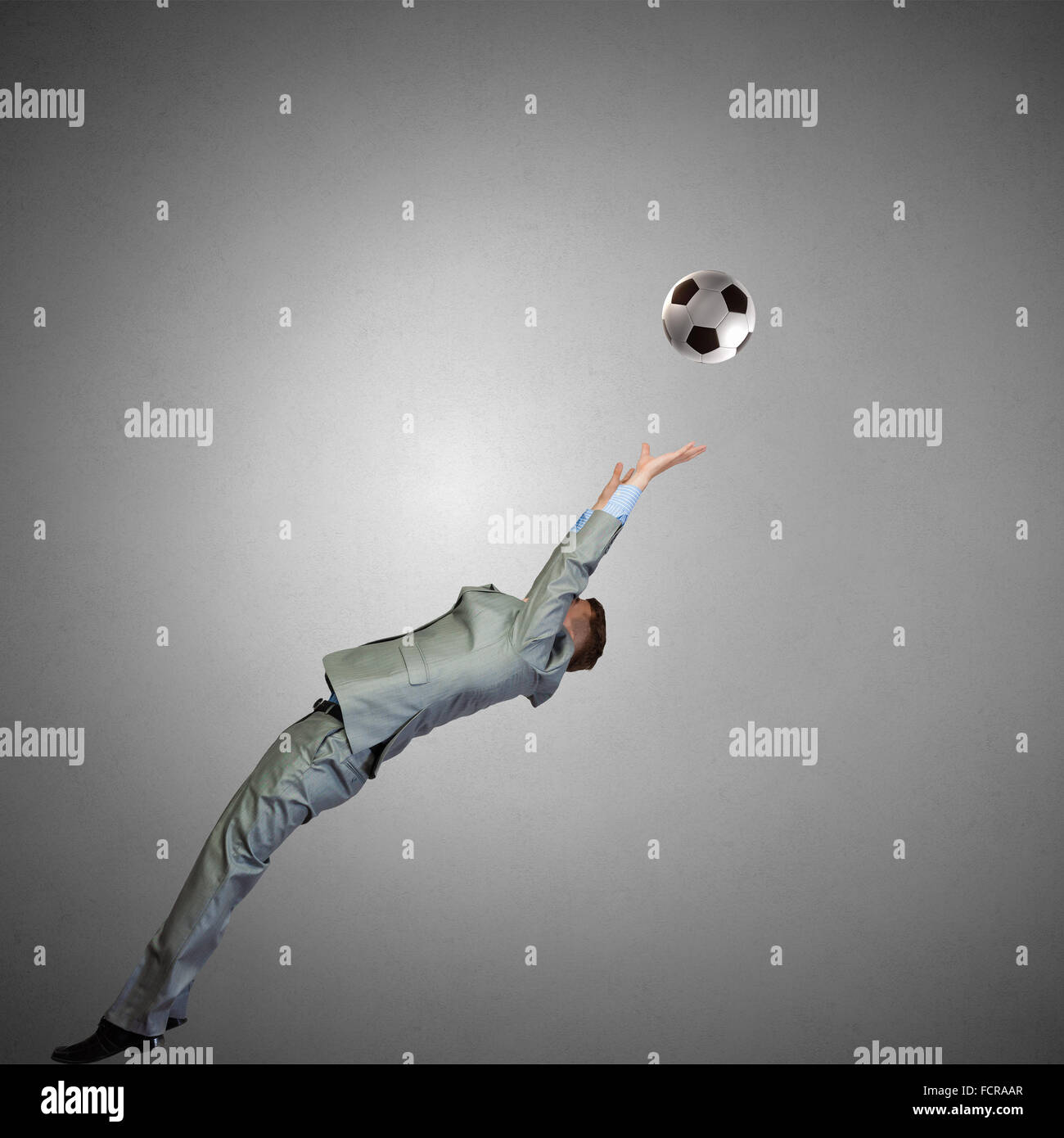 Businessman in suit catching soccer ball in jump Stock Photo - Alamy
