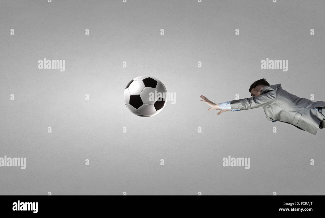Businessman in suit catching soccer ball in jump Stock Photo - Alamy
