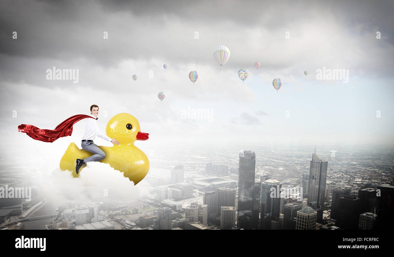 Young happy businessman riding yellow rubber duck Stock Photo - Alamy