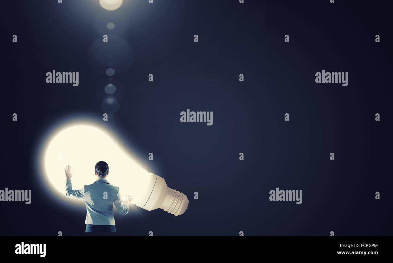 Back view of businesswoman and big glowing light bulb Stock Photo - Alamy