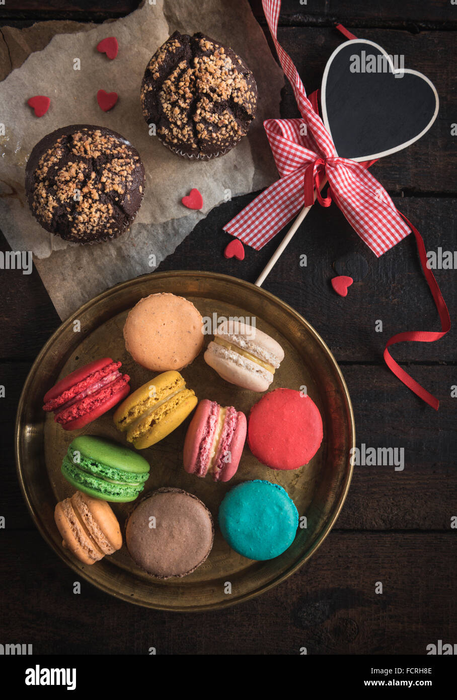 Served chocolate maffins and colorful macaroons cookies on wooden ...