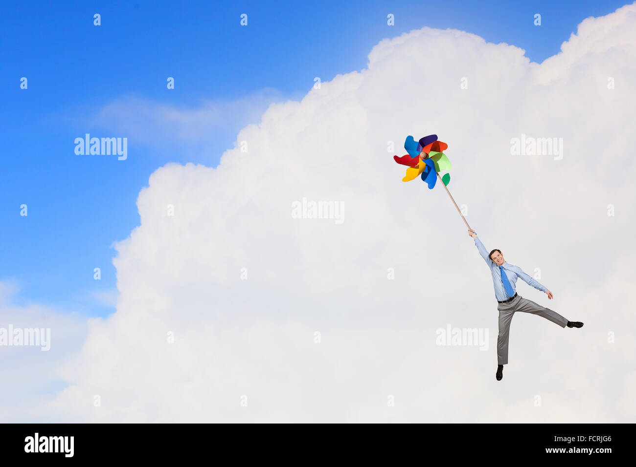 Young happy businessman flying in sky on colorful windmill Stock Photo ...