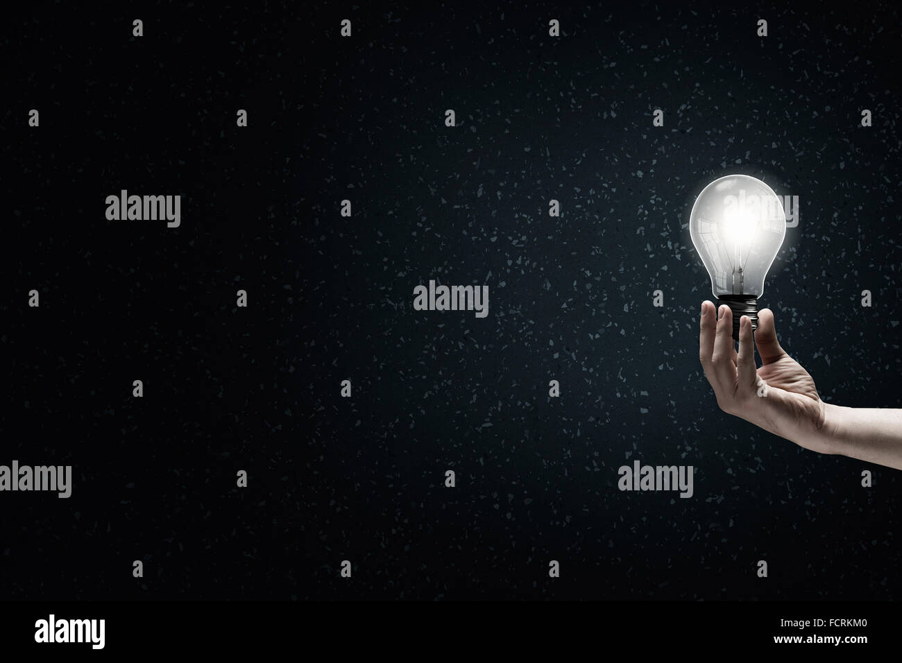 Human hand on dark background holding glass light bulb Stock Photo - Alamy