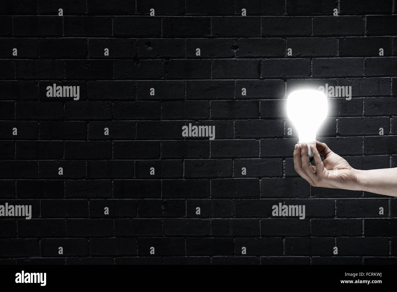 Human hand on dark background holding glass light bulb Stock Photo - Alamy