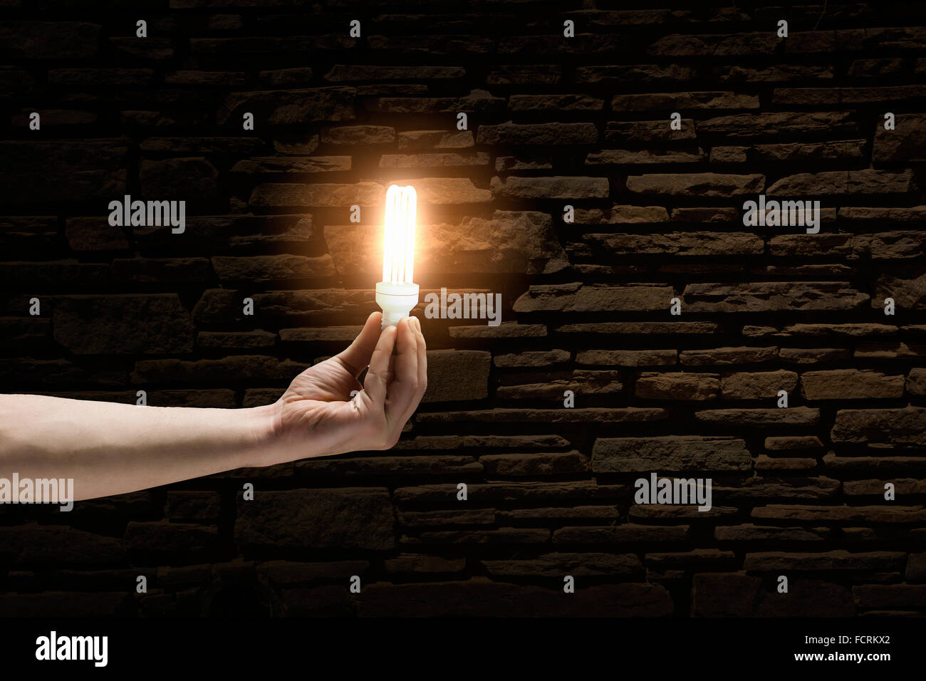 Human hand on dark background holding glass light bulb Stock Photo - Alamy