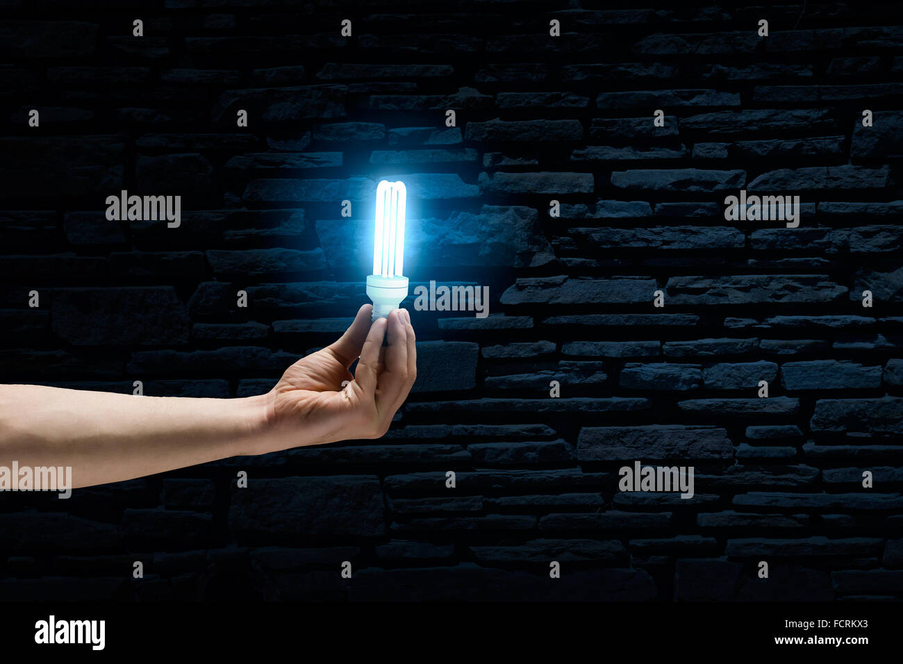 Human hand on dark background holding glass light bulb Stock Photo - Alamy