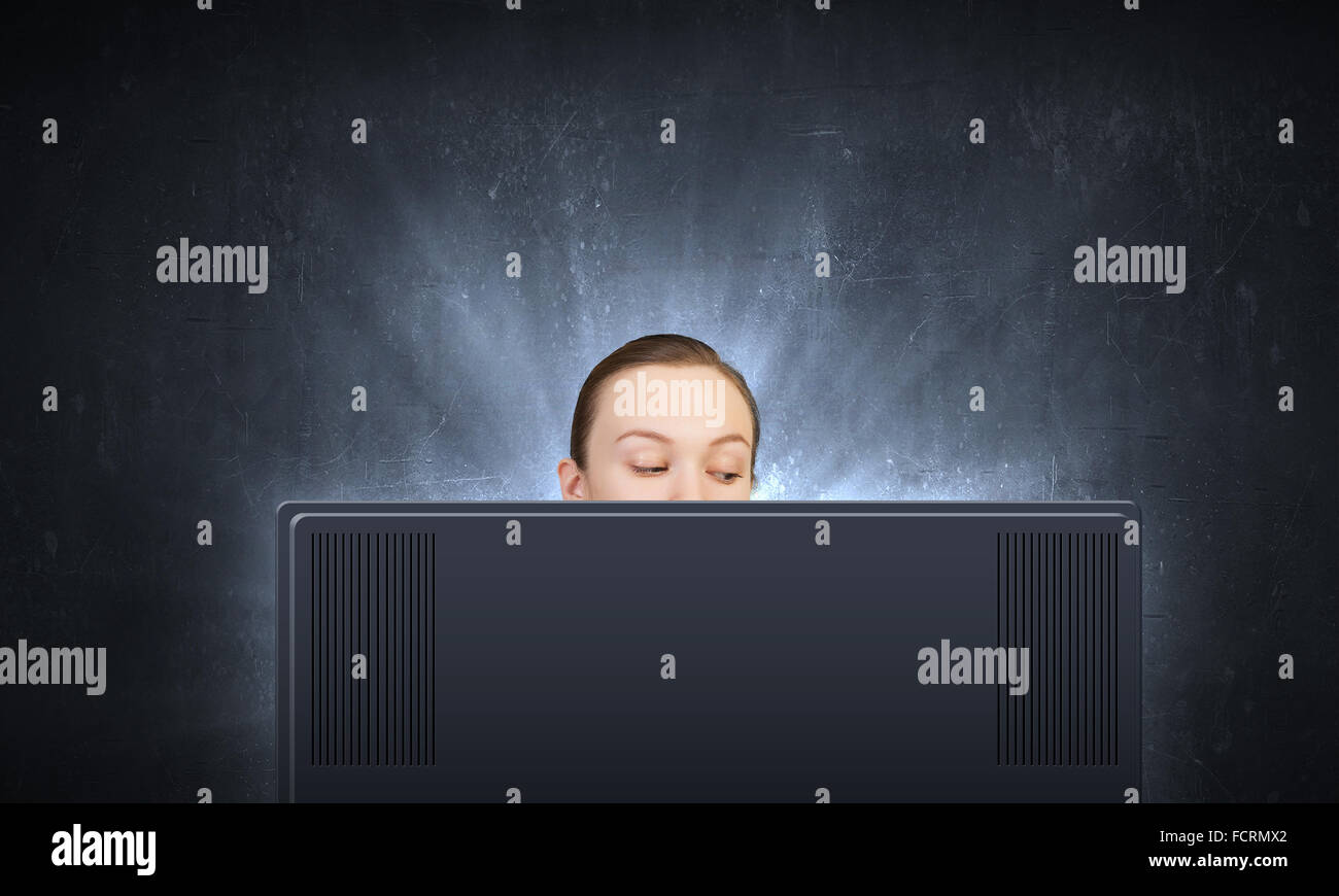 Young woman looking out above laptop monitor Stock Photo - Alamy