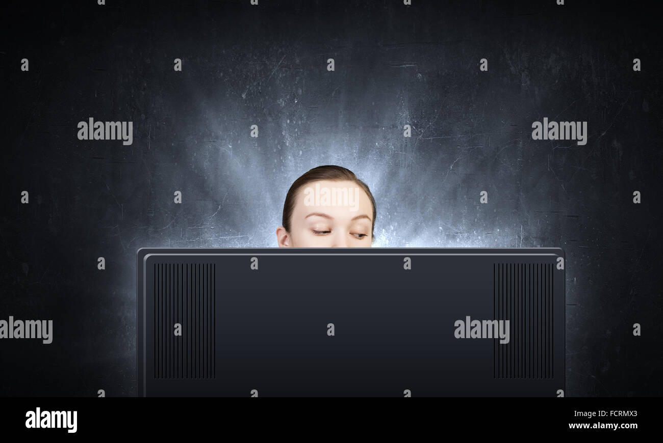 Young woman looking out above laptop monitor Stock Photo - Alamy