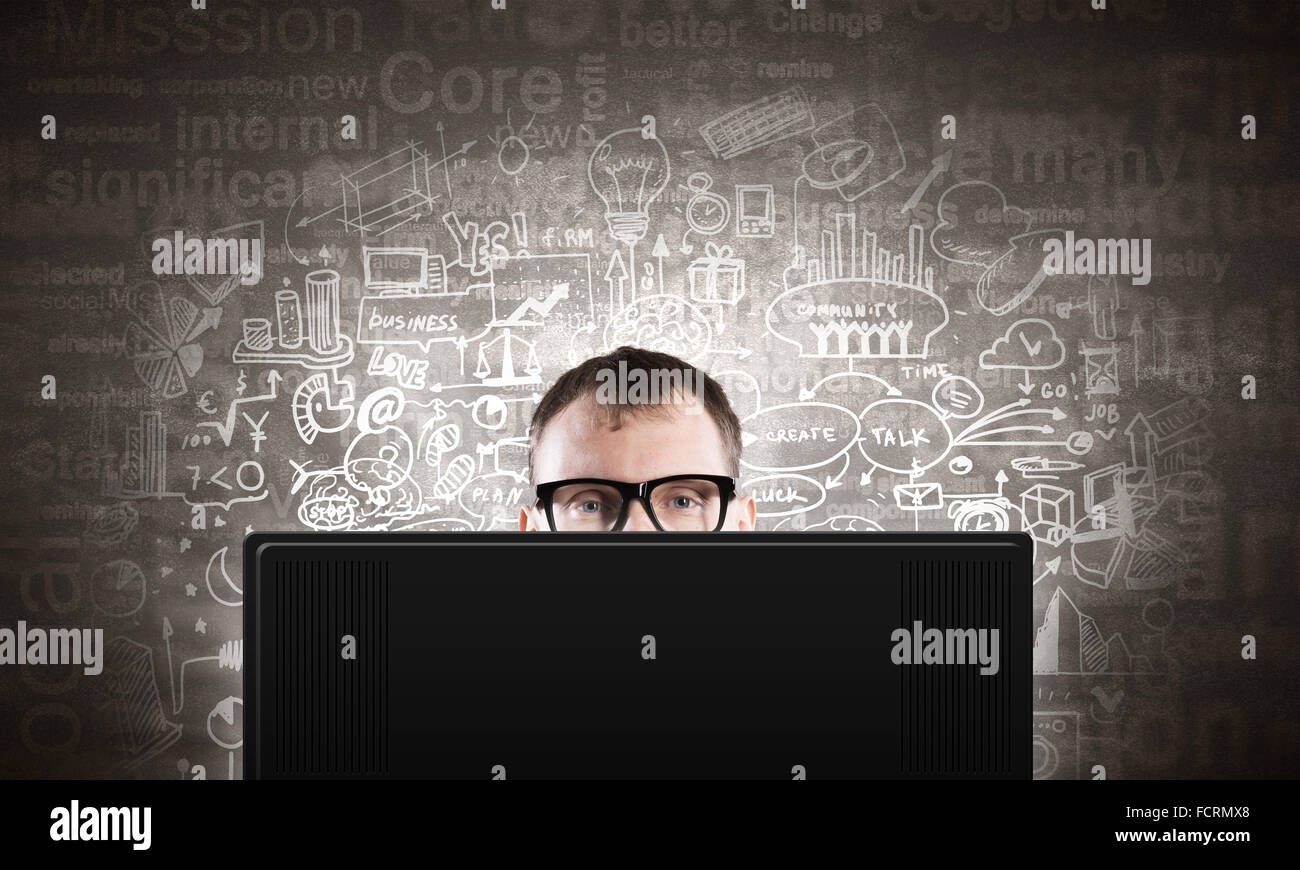 Young man looking out above laptop monitor Stock Photo - Alamy